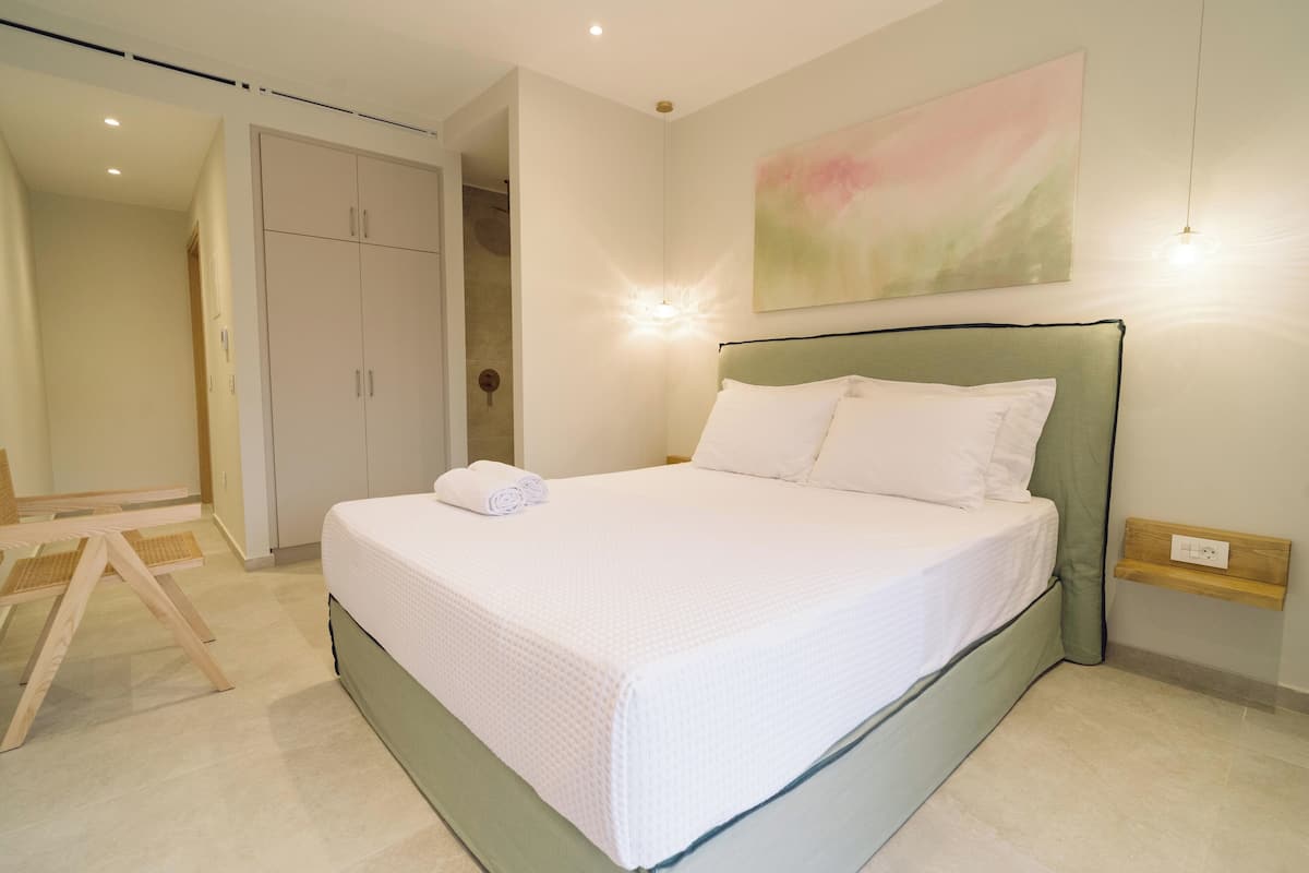 Quarto com cama, guarda-roupa e luminária fixada na parede.