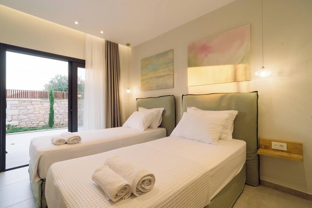Quarto de hotel com duas camas, uma janela grande e vista para o exterior.