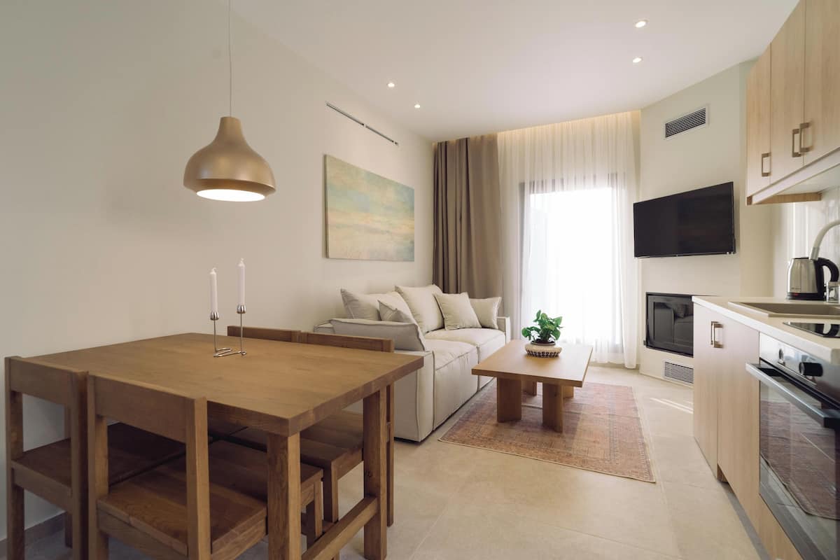 Uma sala de estar moderna com uma mesa de jantar de madeira, sofá e televisão na parede.