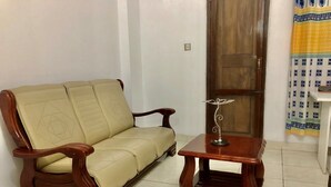 Um sofá de madeira e uma mesa de centro de madeira em um quarto com piso de azulejos e uma porta de madeira.