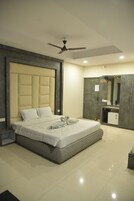 Quarto moderno com cama grande, ventilador de teto, guarda-roupa e um frigorífico pequeno.