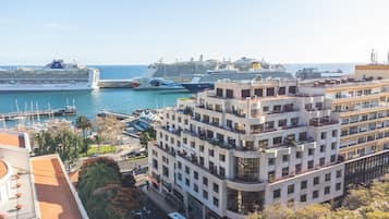 Paisagem costeira com edifícios modernos, um porto com navios de cruzeiro e uma vista clara do mar.