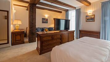 Quarto de hotel com uma cama grande, mobiliário de madeira, televisão de tela plana e vista para o exterior.