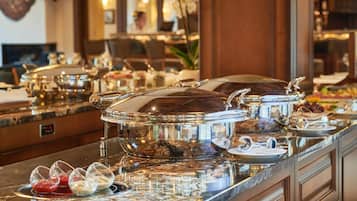Disposição de buffet com diversos recipientes de comida e travessas sobre um balcão de mármore.