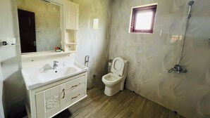 Uma casa de banho com lavatório, sanita e chuveiro.