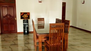 Uma área de refeições com mesa e cadeiras de madeira, um objeto decorativo na parede e uma porta.