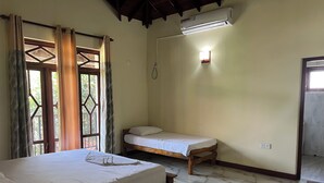 Quarto com uma cama, uma cama adicional, janela com cortinas, ar condicionado e uma luminária fixada na parede.