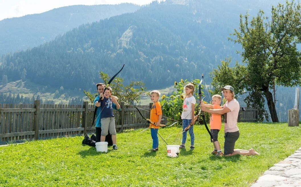 Um grupo de pessoas pescando perto de uma cerca de madeira, com montanhas ao fundo.