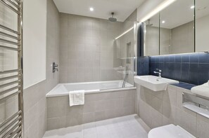 Uma casa de banho moderna com banheira, lavatório e sanita.