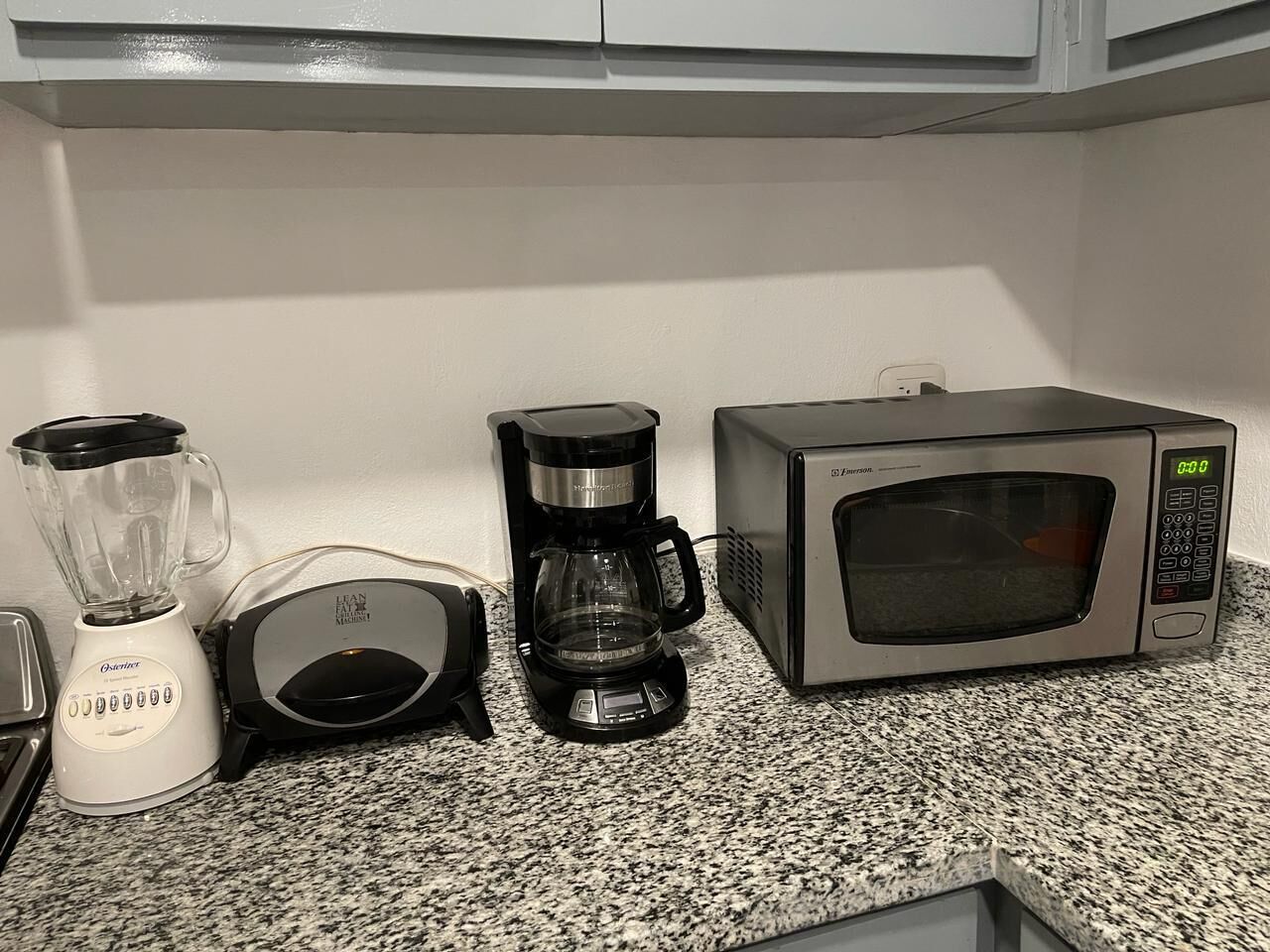 Cozinha com liquidificador, máquina de café e micro-ondas em bancada de granito.
