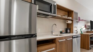 Uma cozinha moderna com eletrodomésticos de aço inoxidável, armários de madeira e micro-ondas embutido.