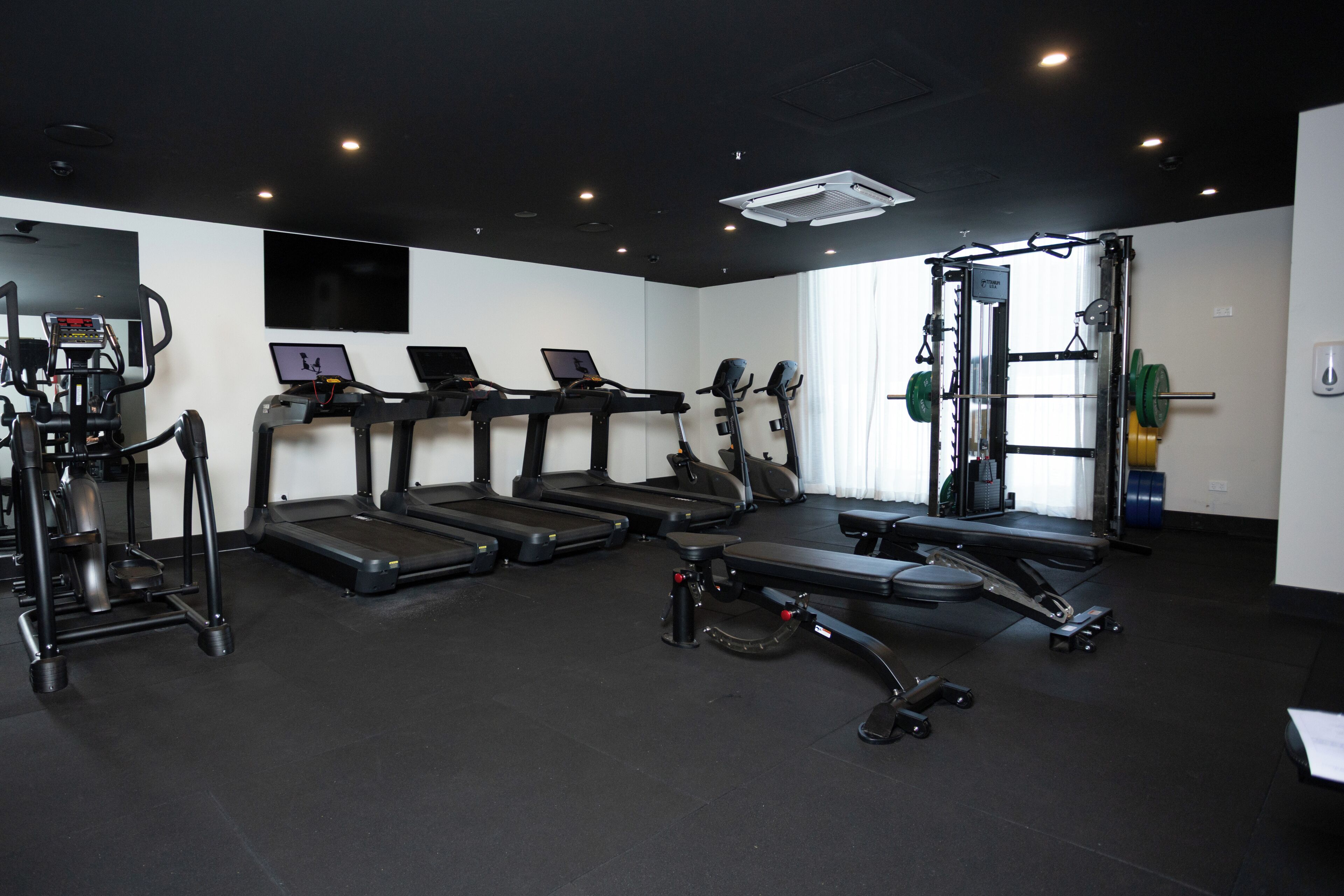Uma academia com esteiras, elípticos e equipamentos de musculação.