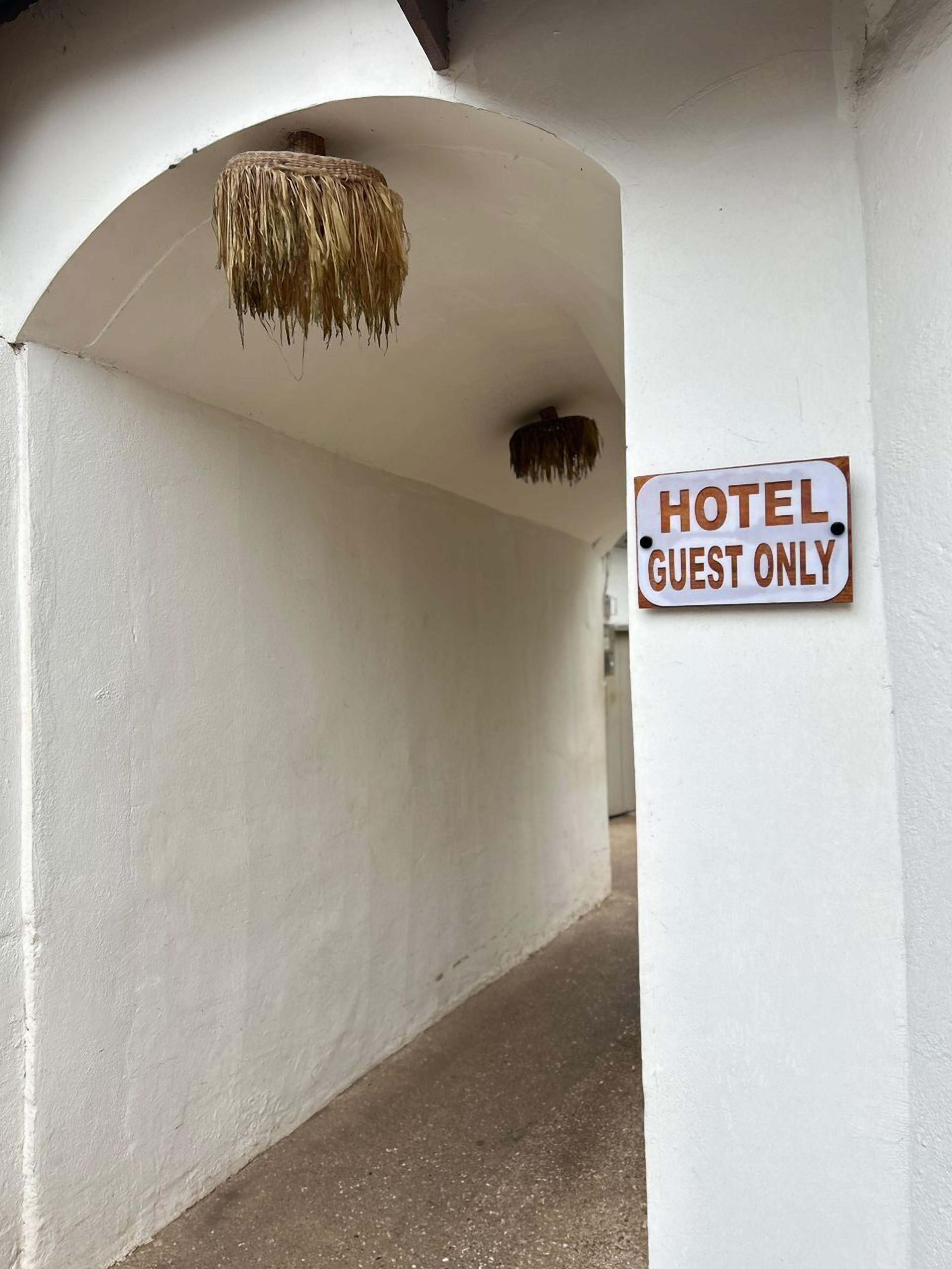 Um corredor com uma placa que diz 'SÓ HÓSPEDES DO HOTEL'.