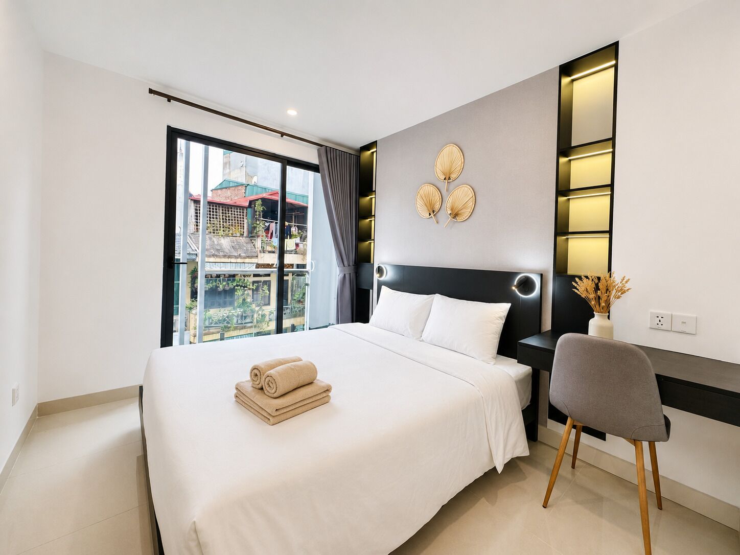 Quarto moderno com uma cama grande, uma escrivaninha e vista através de uma porta de correr.