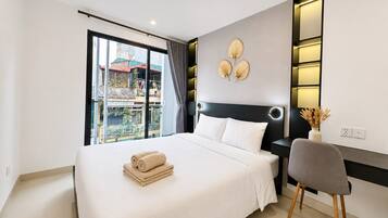 Quarto moderno com uma cama grande, uma escrivaninha e vista através de uma porta de correr.