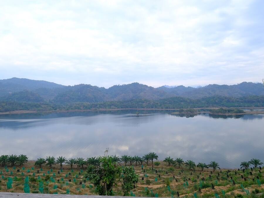 Um lago calmo com uma cadeia de montanhas arborizadas ao fundo.