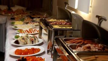 Uma mesa de buffet com diversos alimentos e um espaço para grelhados.