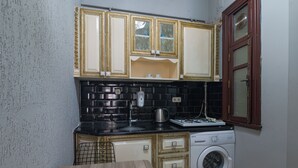 Cozinha compacta com mesa de madeira, máquina de lavar e pia.