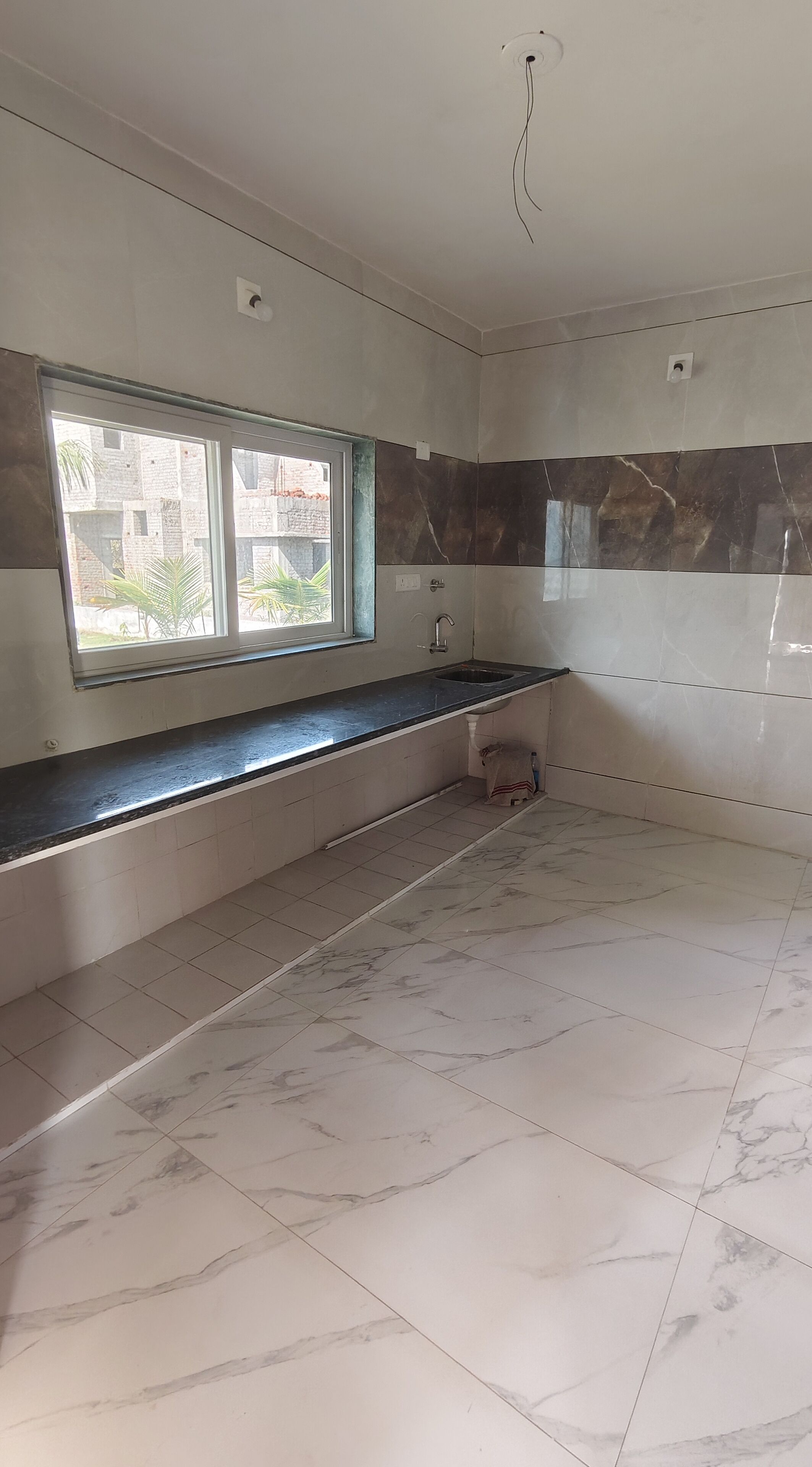 Um quarto com janela, pia e chão revestido de azulejos.