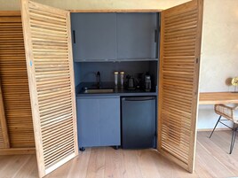 Uma cozinha compacta com geladeira embutida, pia e cafeteira.