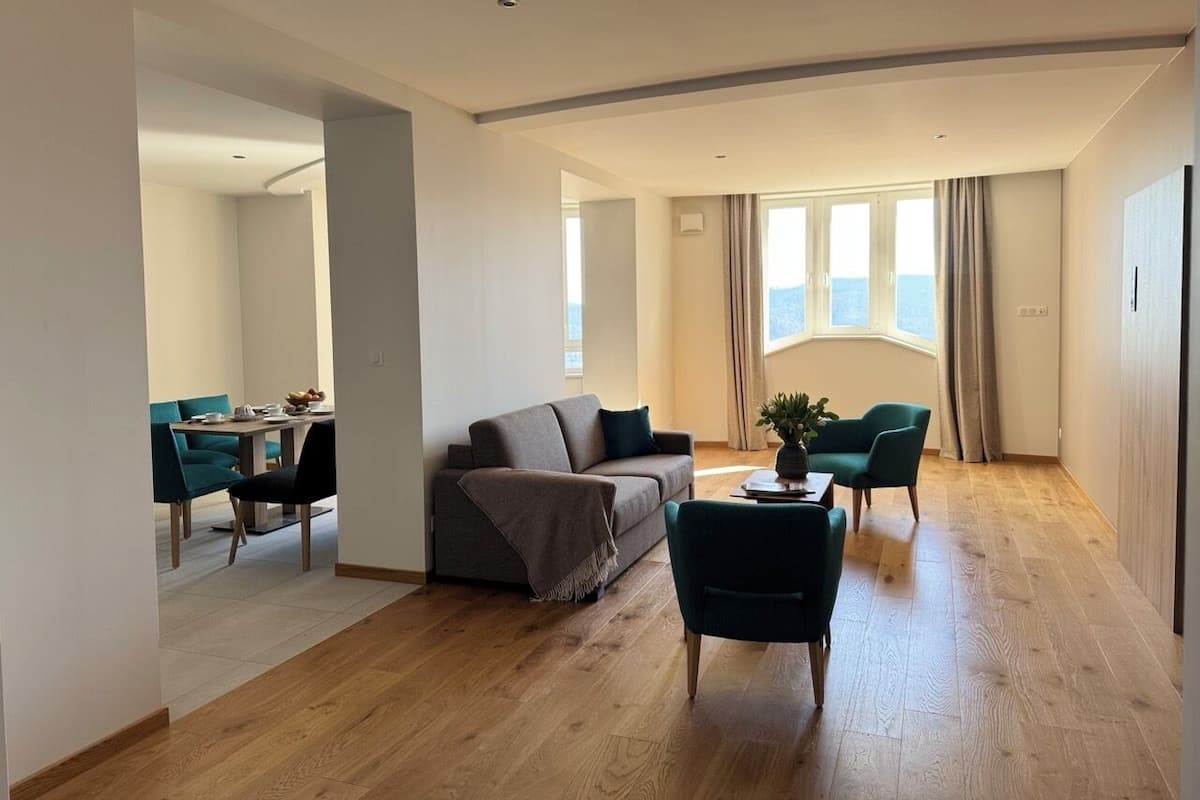 Uma sala de estar moderna com sofá, poltronas e um espaço de jantar com mesa e cadeiras.
