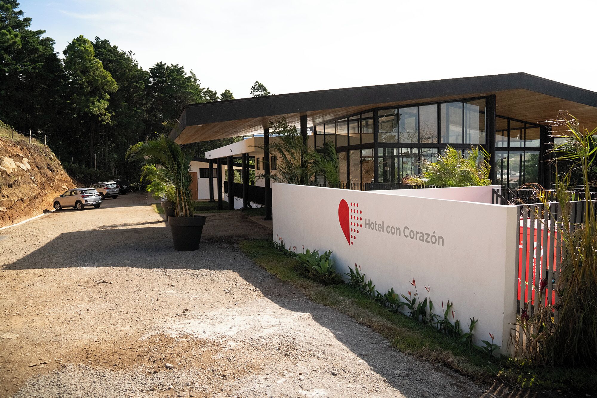 Entrada de hotel moderna com um letreiro grande, uma galeria coberta e um caminho de acesso de cascalho.