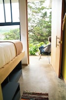 Um quarto com cama, uma cadeira e vista para um jardim.