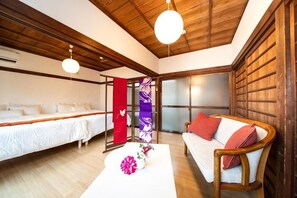 Quarto com cama, sofá, mesa com um vaso e porta deslizante.