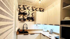Uma cozinha compacta com armários brancos, painel de fundo de mármore e forno embutido.
