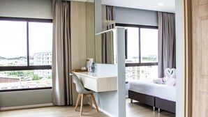Quarto de hotel moderno com escrivaninha, cadeira e cama.
