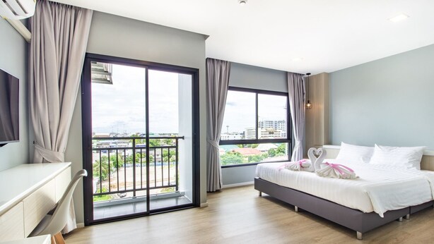 Quarto de hotel moderno com cama, escrivaninha e varanda com vista para a cidade.