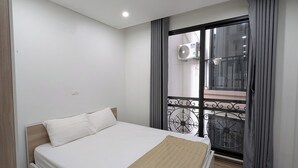 Quarto de hotel moderno com uma cama grande, uma varanda com guarda-corpo metálico e um ar condicionado fixado na parede.