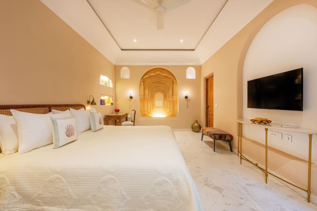 Um quarto espaçoso com uma cama grande, televisão e um arco decorativo.