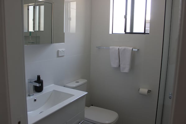 Uma casa de banho moderna com lavatório branco, sanita e cabine de duche em vidro.