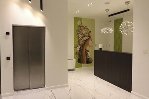 Um interior moderno com piso de mármore, um balcão de recepção e uma obra de arte na parede.