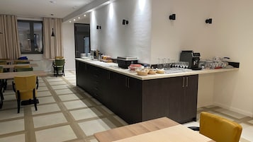 Uma cozinha moderna com armários escuros, uma ilha central e uma área de refeições com cadeiras amarelas e uma mesa de madeira.