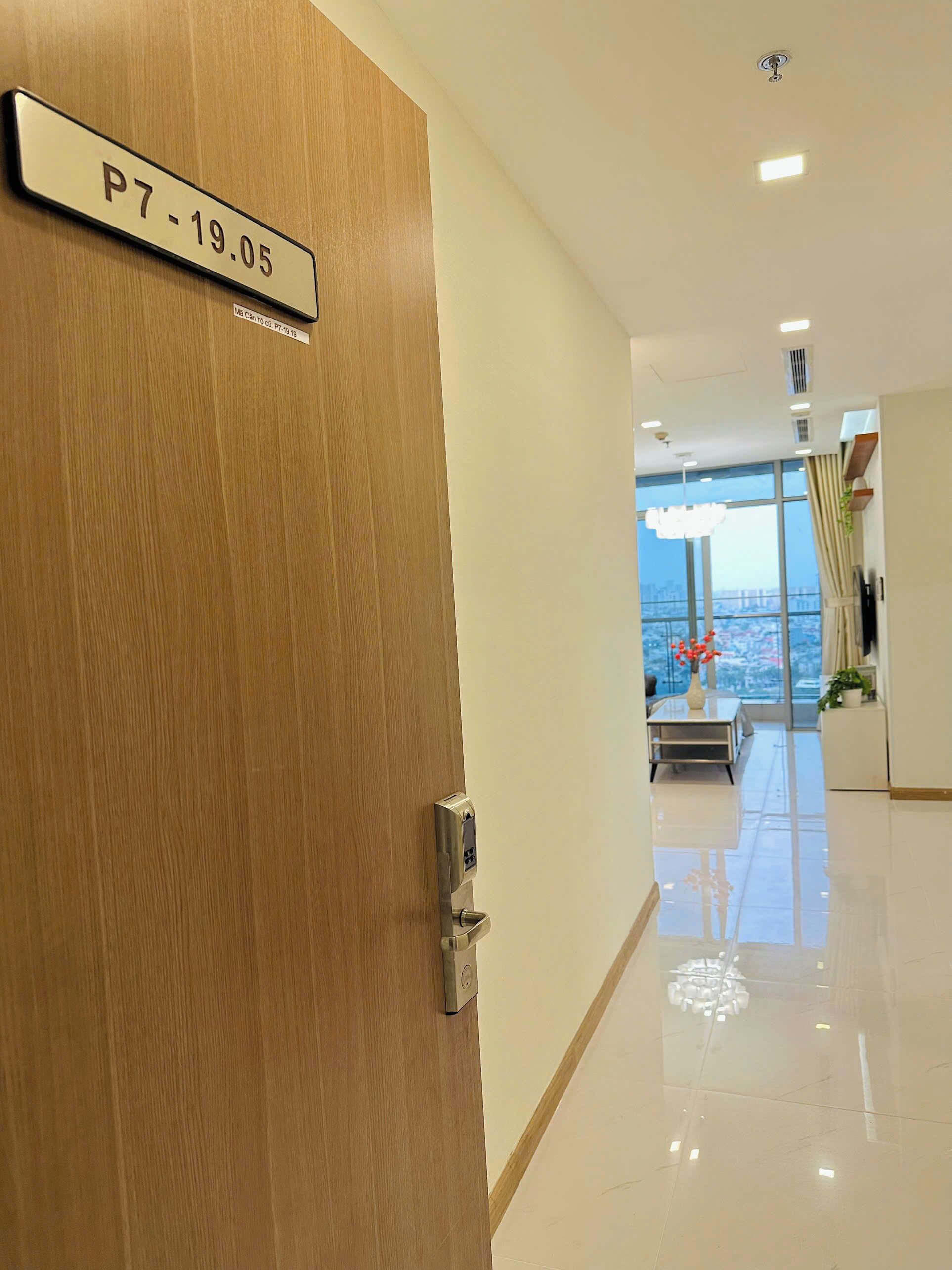 Um corredor de hotel com uma porta de madeira identificada com a etiqueta “P7-19.05”.