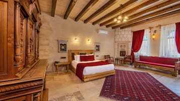 Quarto tradicional com cama de madeira, sofá vermelho e tapete estampado.