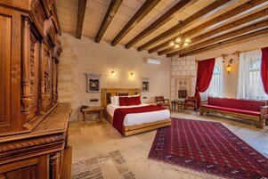 Quarto tradicional com cama de madeira, sofá vermelho e tapete estampado.