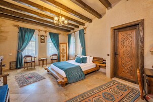 Quarto tradicional com cama, móveis de madeira e uma grande porta entalhada.