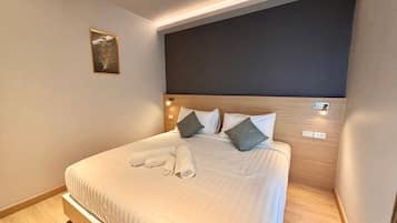 Cama bem arrumada com almofadas, cabeceira e uma pequena moldura na parede.