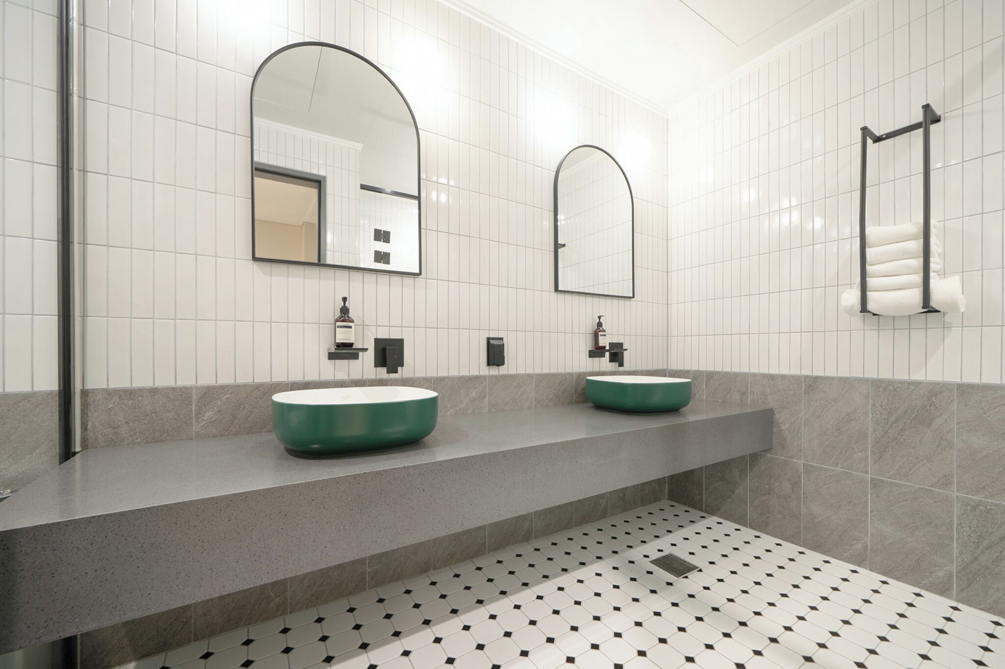 Um banheiro moderno com duas pias, espelhos grandes e piso revestido de azulejos.