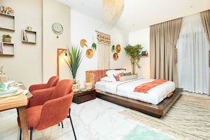 Quarto moderno com cama, escrivaninha, cadeiras e uma janela grande com cortinas.