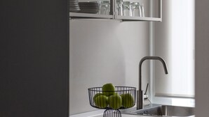 Uma cozinha moderna com armários brancos, uma prateleira embutida com a etiqueta 