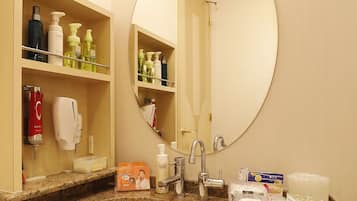 Casa de banho com um espelho grande, prateleiras com artigos de higiene e um secador de cabelo.