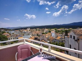 Uma varanda com vista para uma cidade, uma mesa com um letreiro de 'Welcome' e uma cadeira.