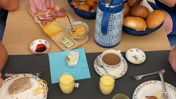 Uma mesa de café da manhã com pratos, talheres e diversos alimentos.