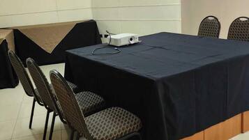 Uma sala de conferência com uma mesa grande, cadeiras e um aparelho de ar condicionado no teto.