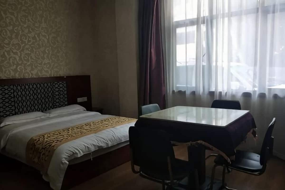 Quarto de hotel com cama, mesa e cadeiras.