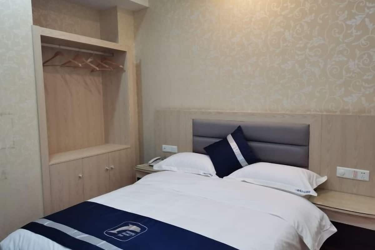 Quarto de hotel com uma cama, um guarda-roupa e uma mesa de cabeceira.